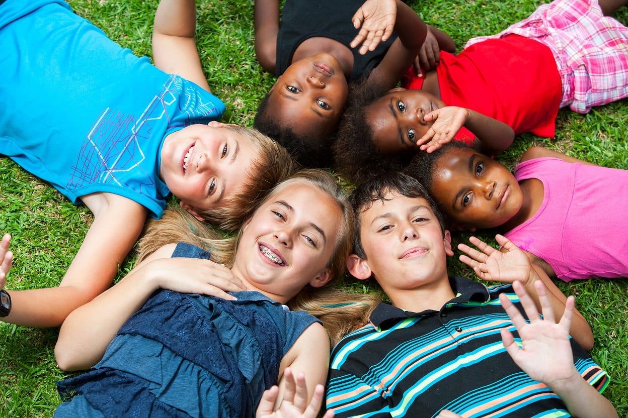 Diverse group og children laying together on grass. – Wadley Chiropractic